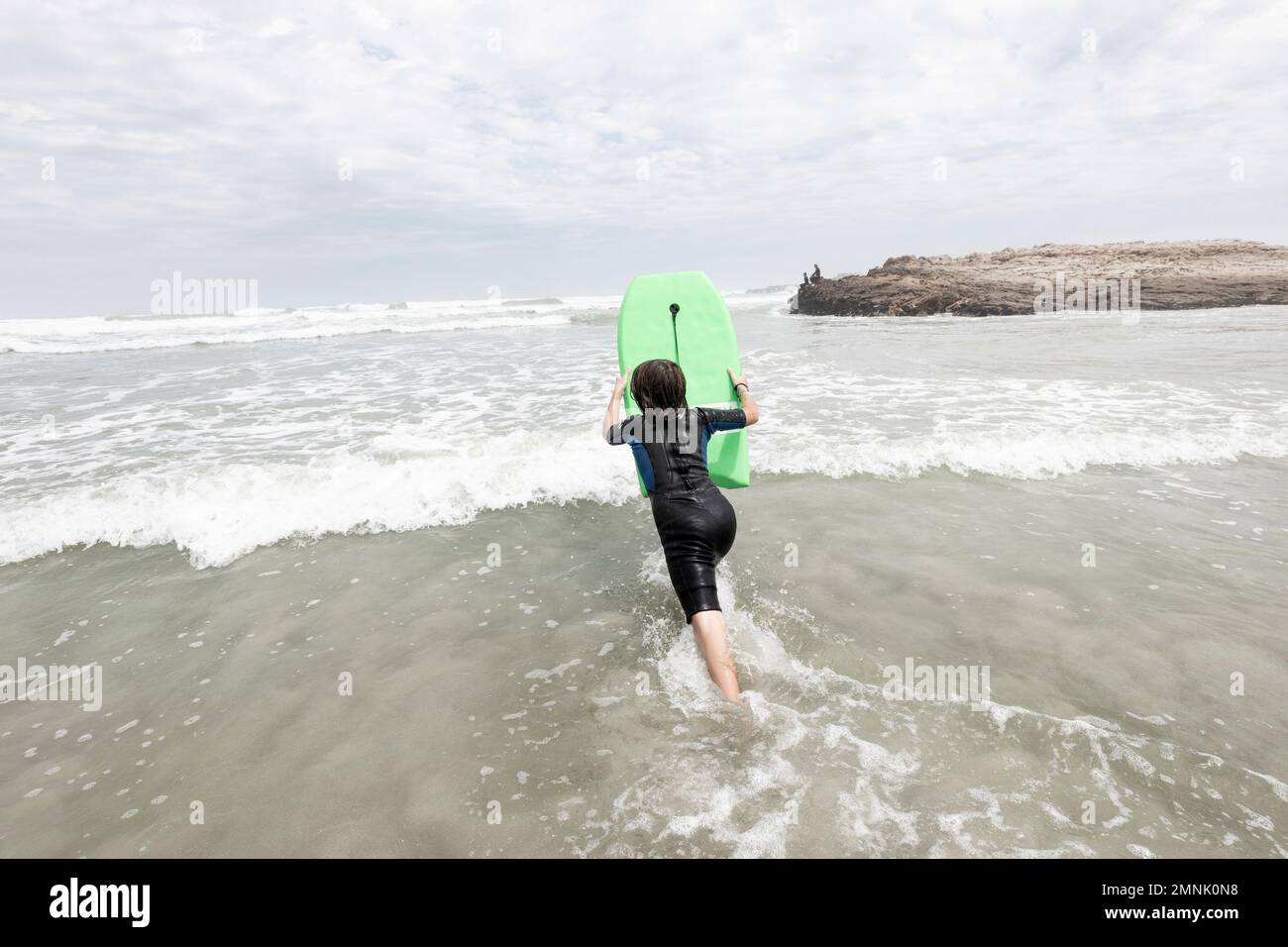 Boy (10-11) bodyboarding on Voelklip beach Stock Photo - Alamy