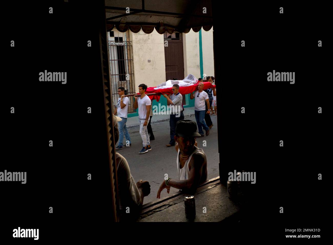 People carry a statue of Jesus Christ past people drinking some beer ...