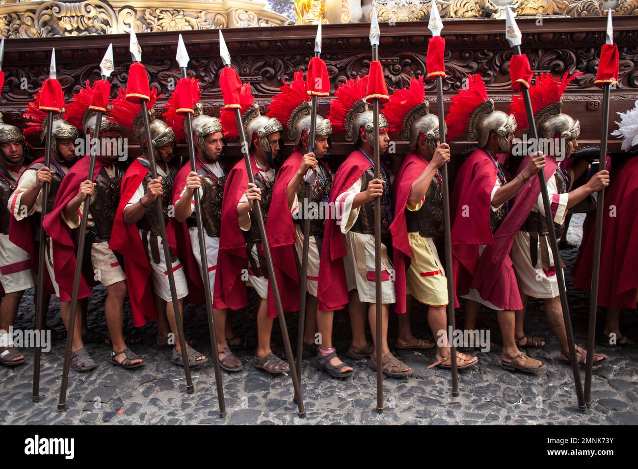 Men dressed as Roman soldiers carry a float featuring a statue of Jesus ...