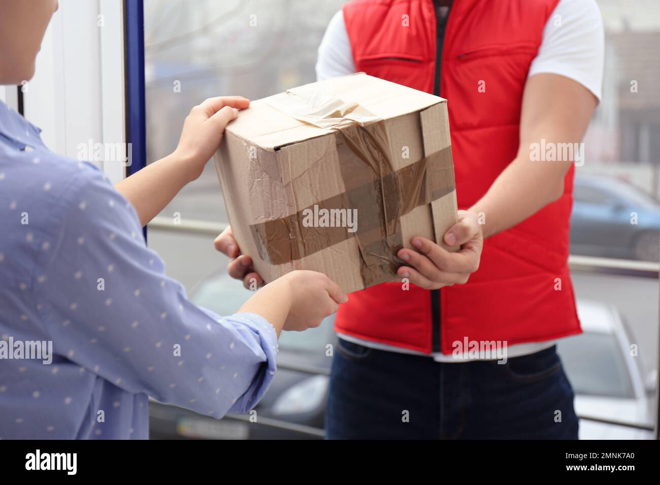 Courier giving damaged cardboard box to client in doorway, closeup ...