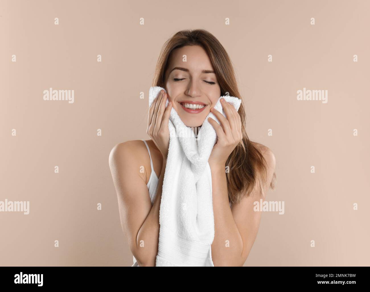 Young woman wiping face with towel on beige background Stock Photo - Alamy