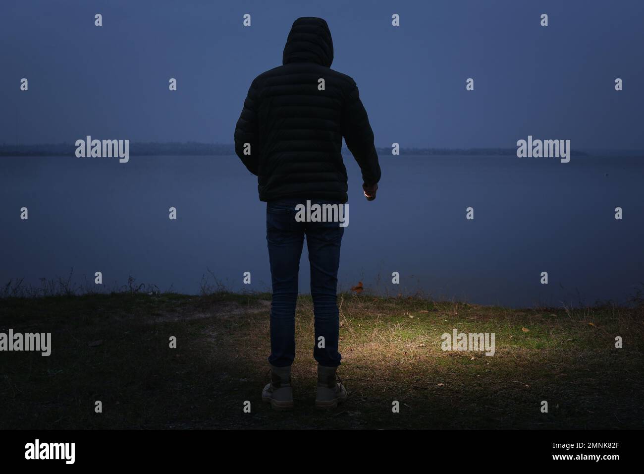 Man with flashlight walking near river in evening Stock Photo - Alamy