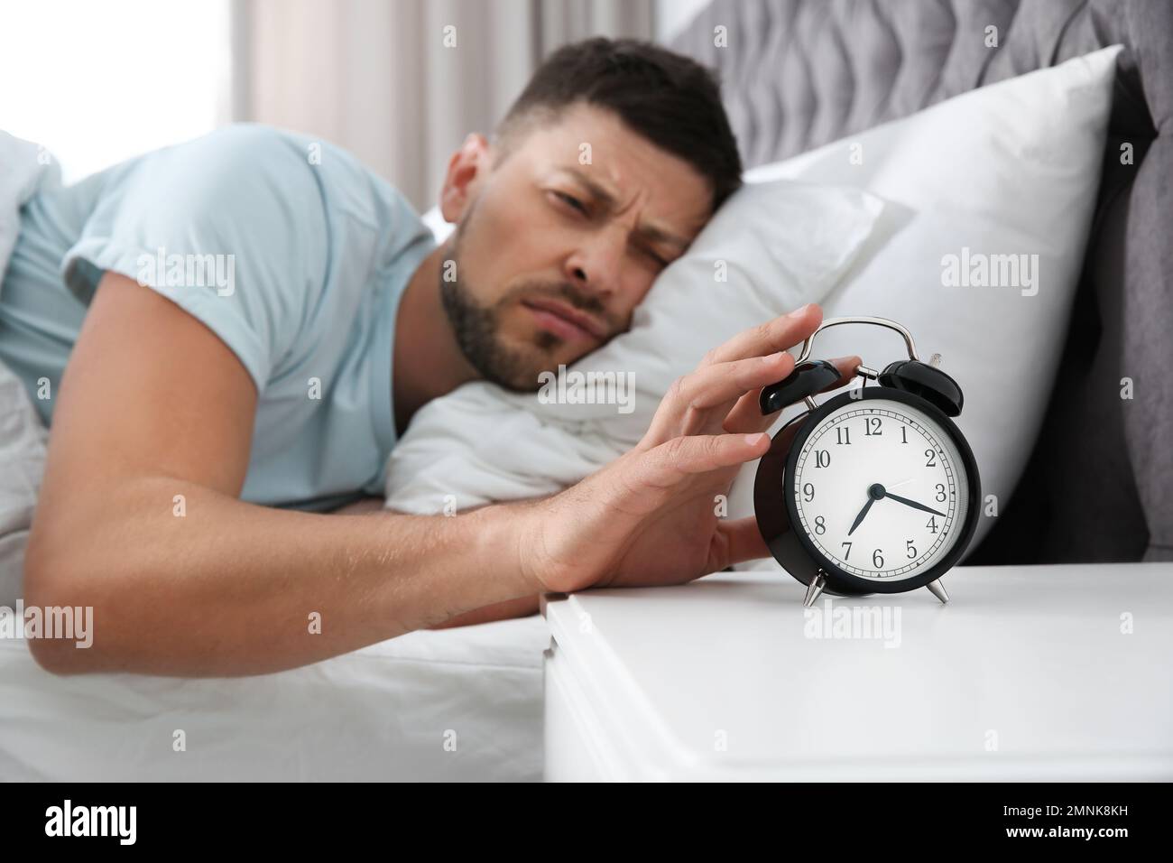 Sleepy Man Turning Off Alarm Clock At Home In Morning Focus On Hand