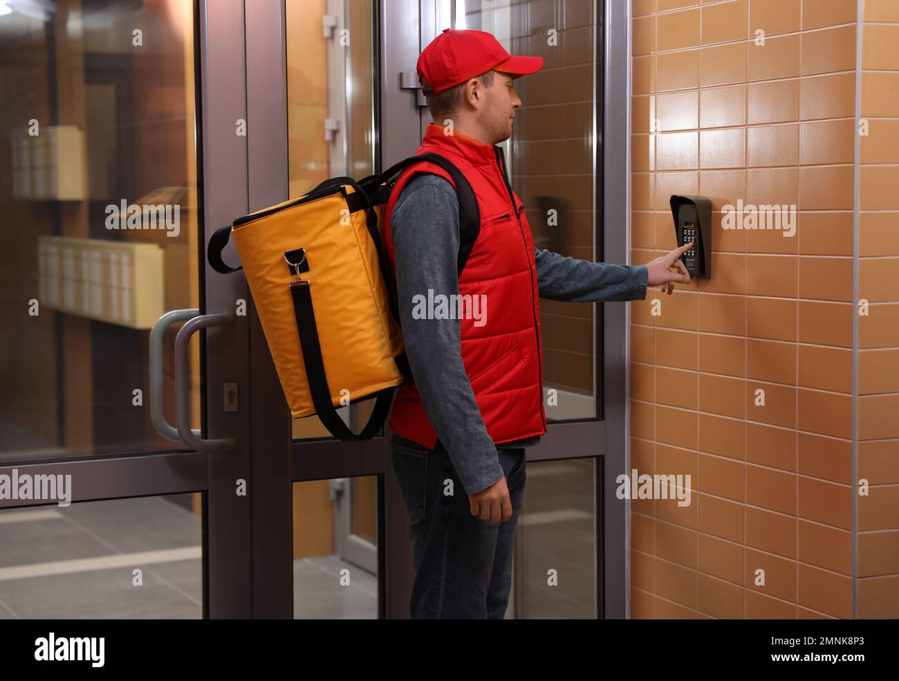Male courier with thermo bag pushing intercom button. Food delivery ...