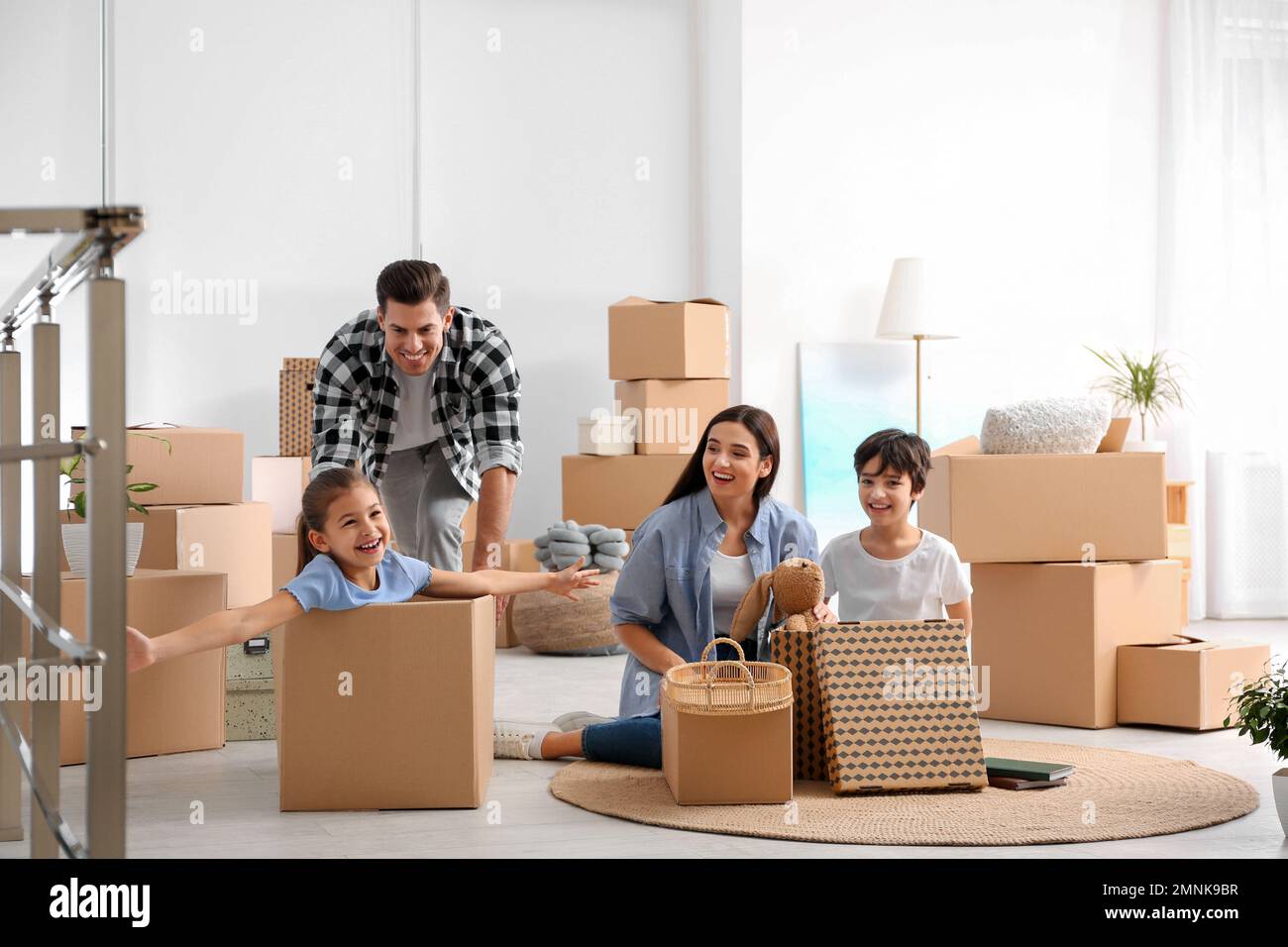 Happy family having fun while unpacking moving boxes at their new home ...