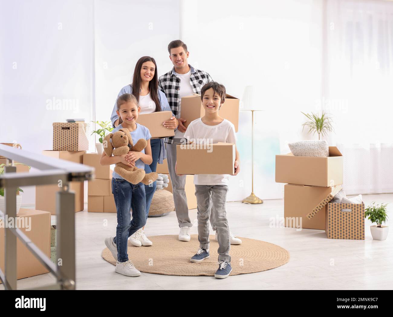 Happy family in room with cardboard boxes on moving day Stock Photo - Alamy