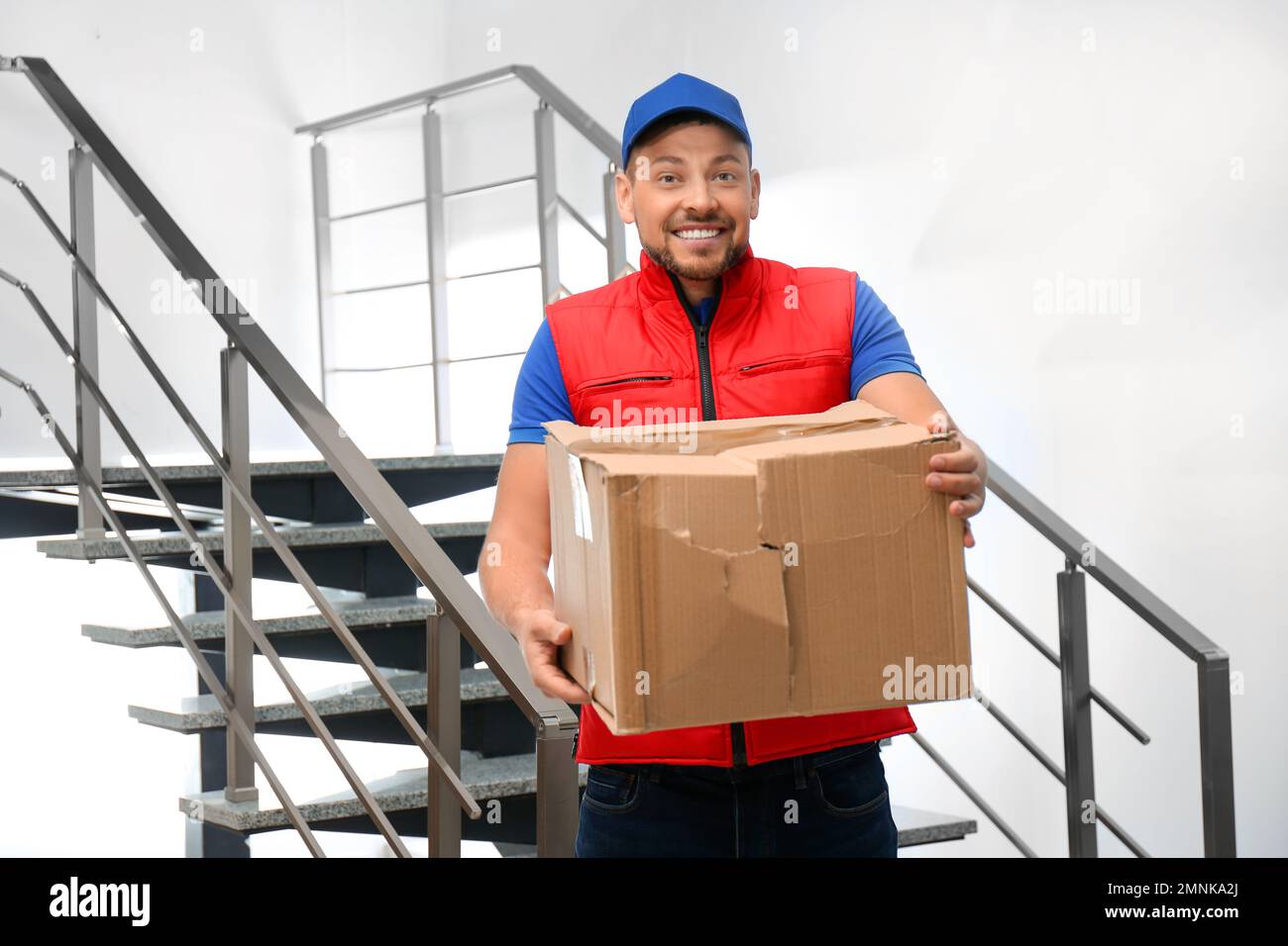 Emotional courier with damaged cardboard box indoors. Poor quality ...