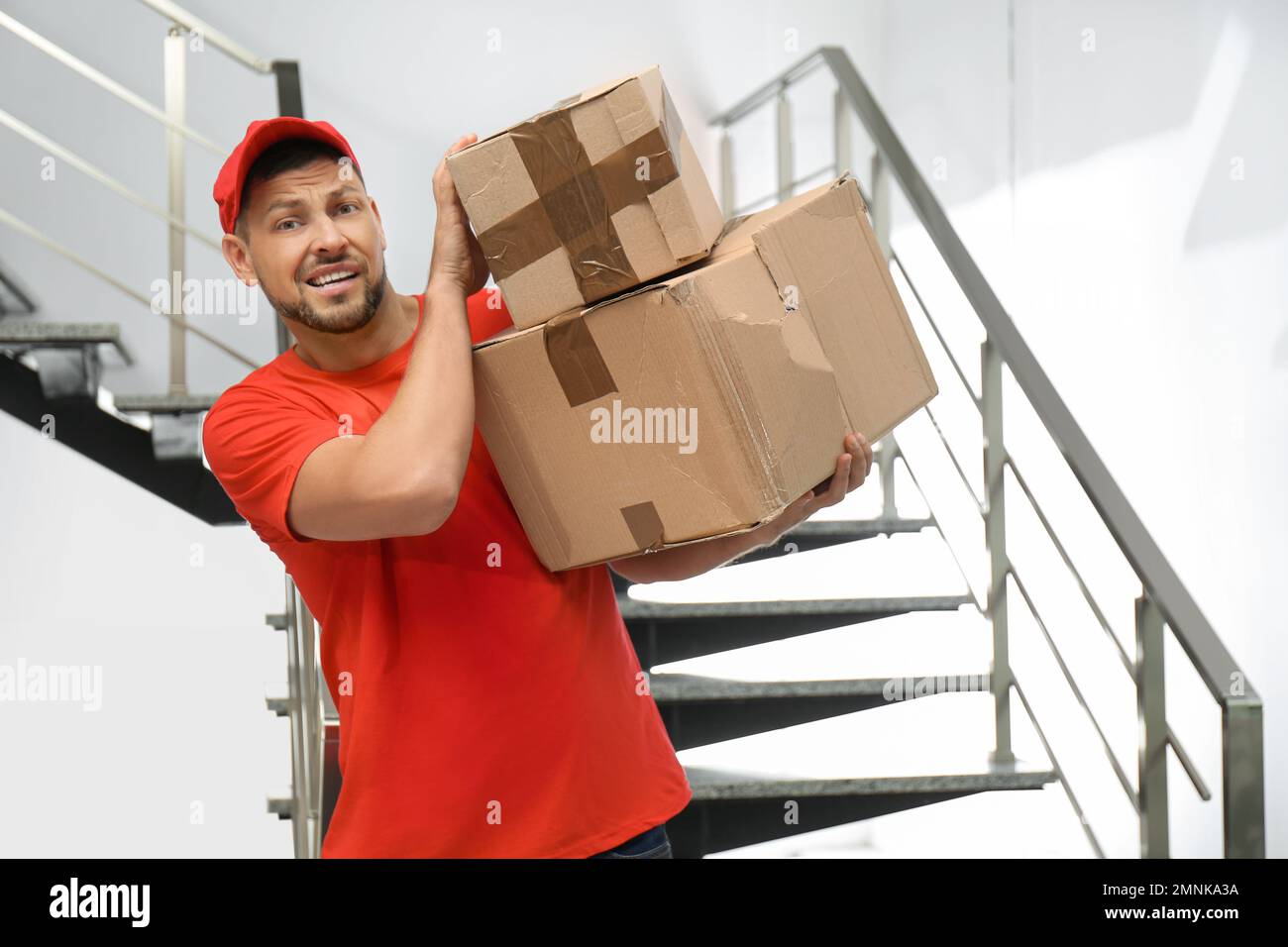 Emotional courier with damaged cardboard boxes indoors. Poor quality ...