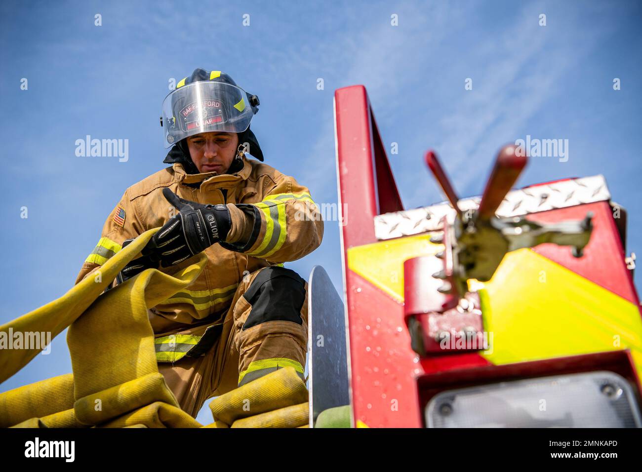 A firefighter from the 422d Fire Emergency Services rolls a fire hose ...