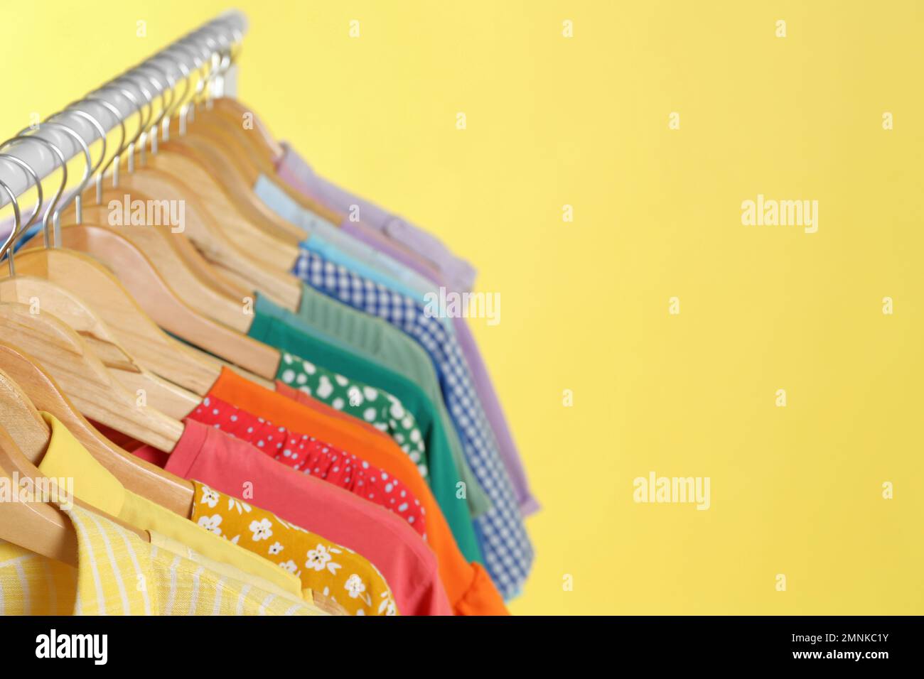 Bright Clothes Hanging On Rack Against Yellow Background Space For Text Rainbow Colors Stock