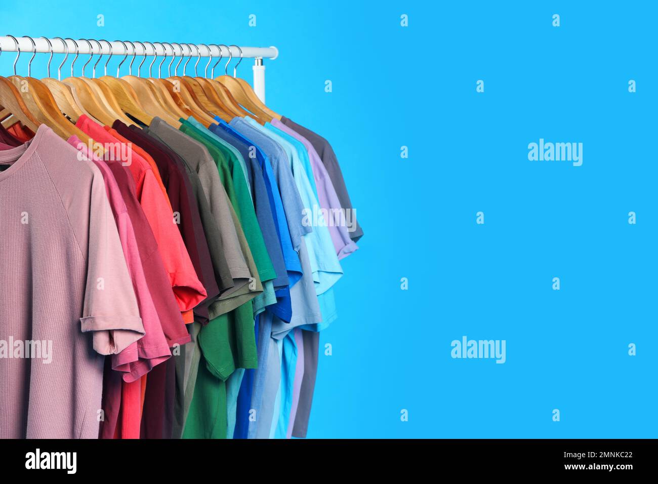Colorful clothes hanging on rack against light blue background. Space ...