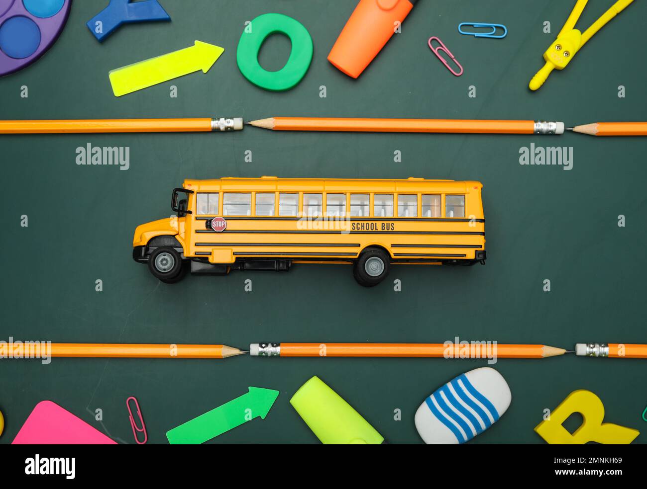 Flat lay composition with yellow school bus and stationery on green ...
