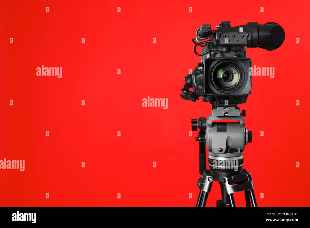 Modern professional video camera on red background. Space for text ...