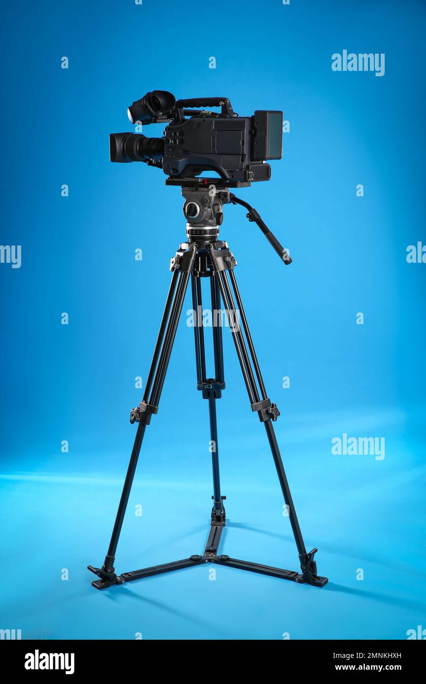 Modern professional video camera on blue background Stock Photo - Alamy
