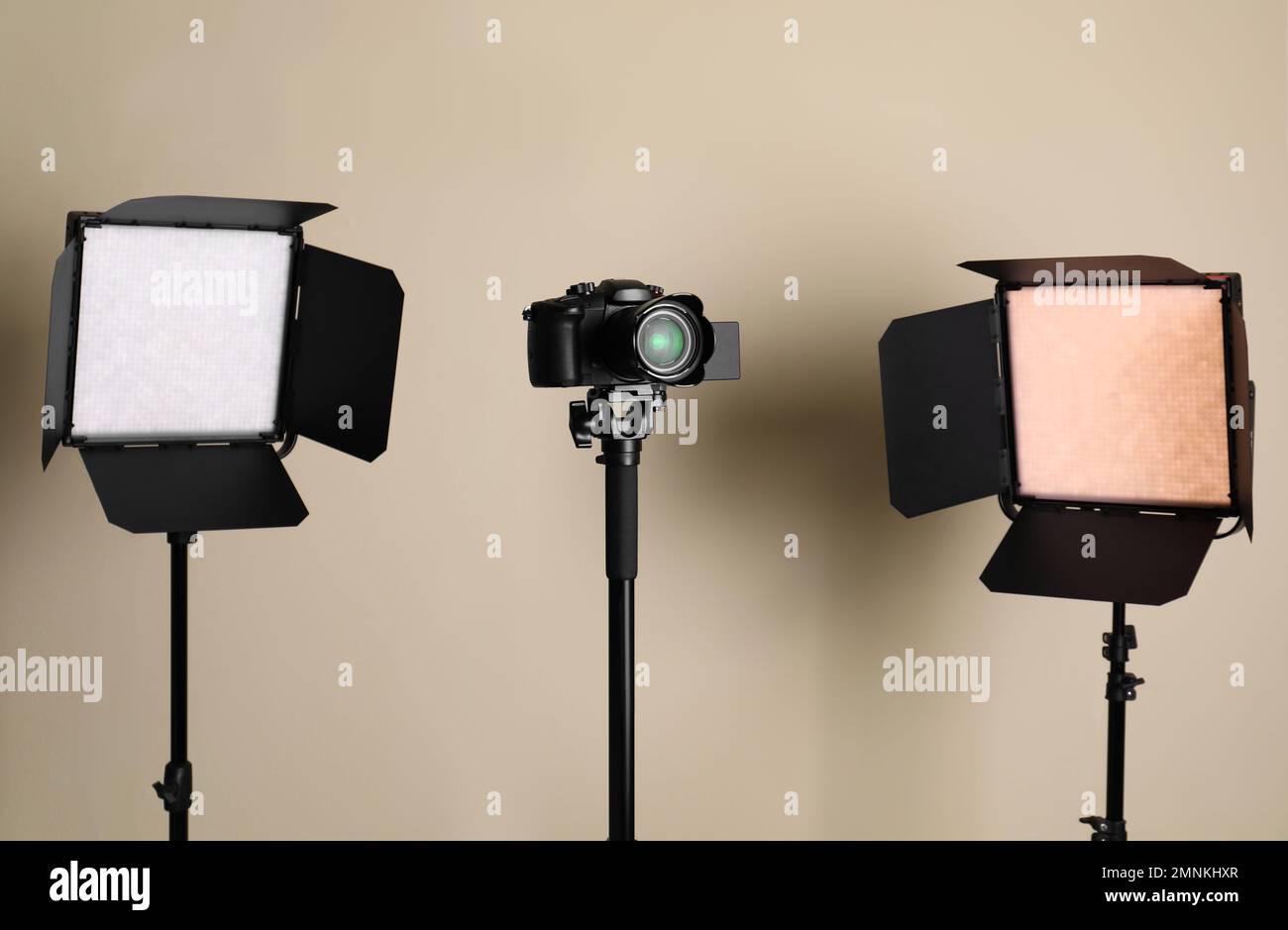 Professional video camera and lighting equipment on beige background ...