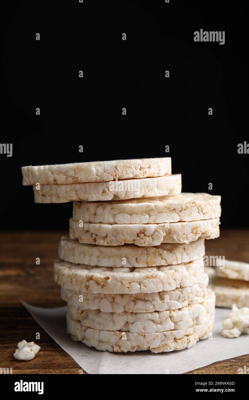 Stack of puffed rice cakes on wooden table against black background ...