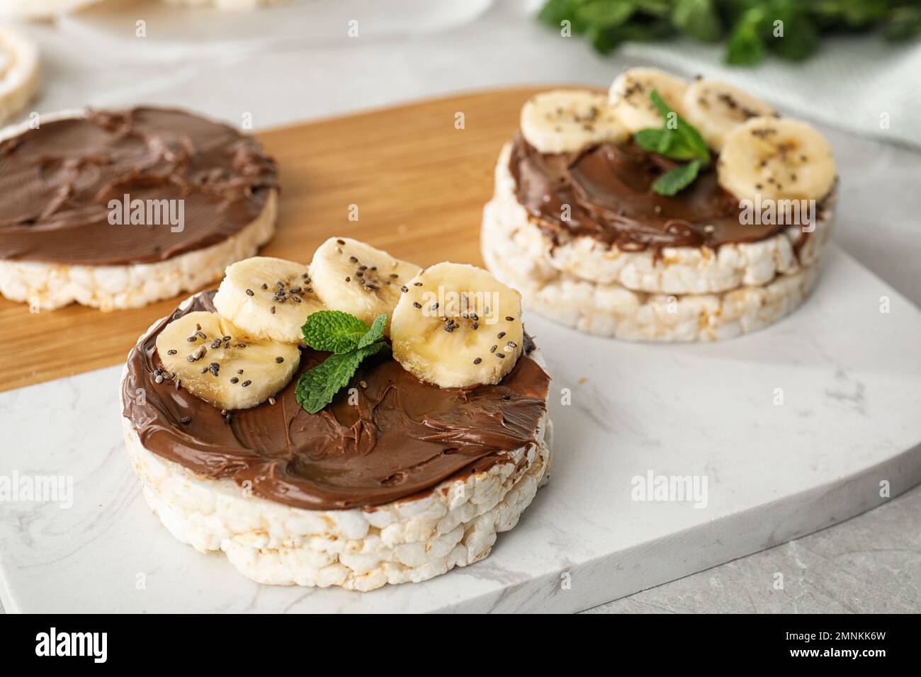 Puffed rice cakes with chocolate spread, banana and mint on board ...