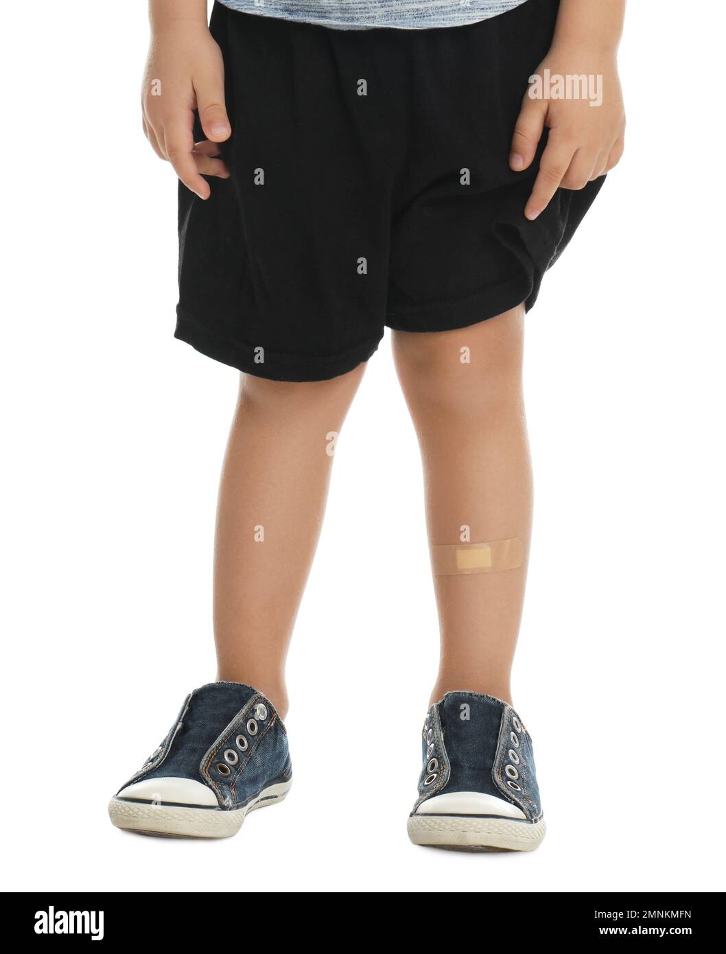Little boy with sticking plaster on leg against white background ...