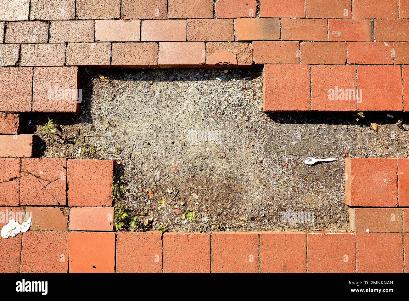Missing Bricks in Sidewalk with Dirt and Plastic Spoon Stock Photo - Alamy