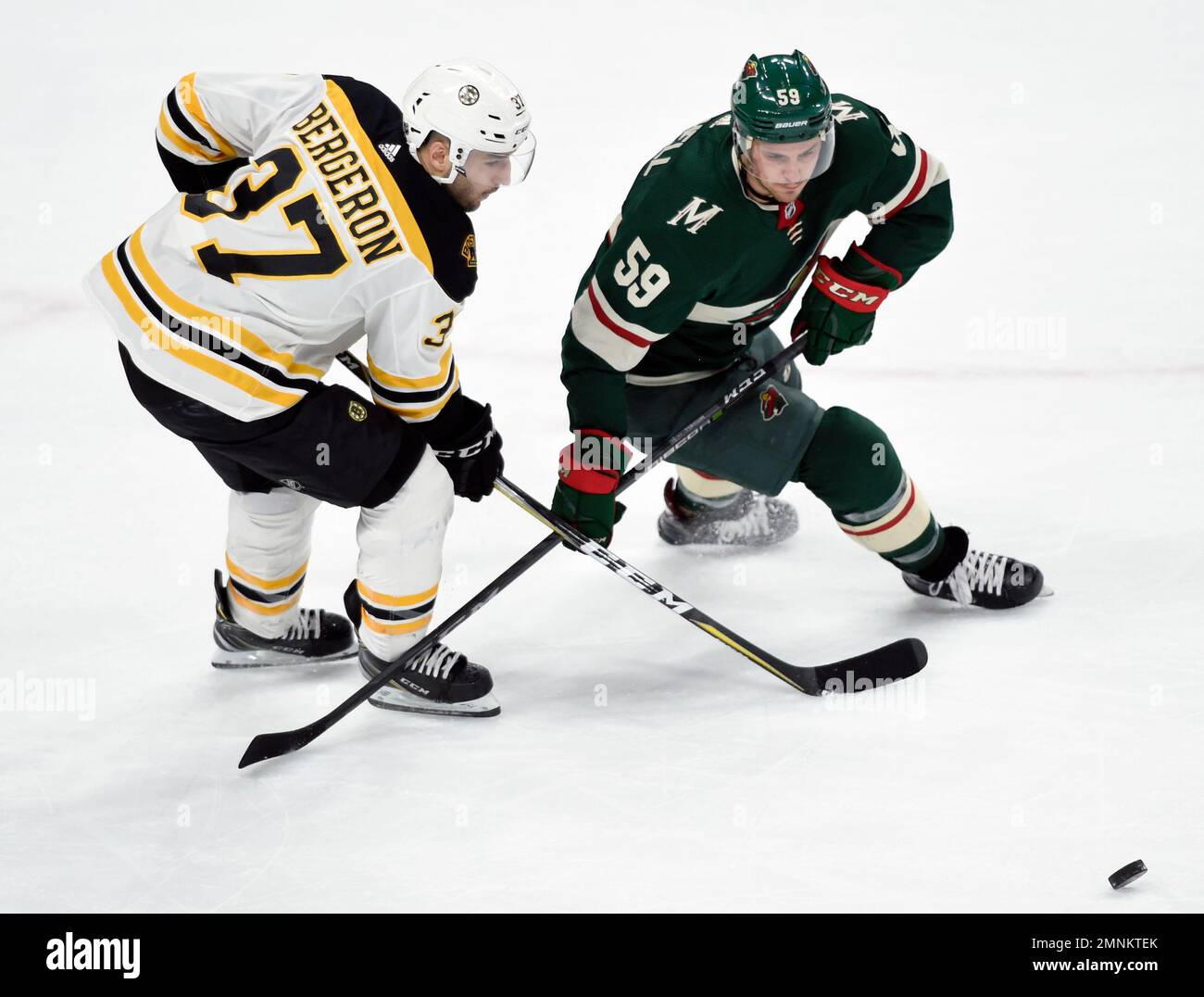 Boston Bruins' Patrice Bergeron (37) and Minnesota Wild's Zack Mitchell (59) skate after the ...