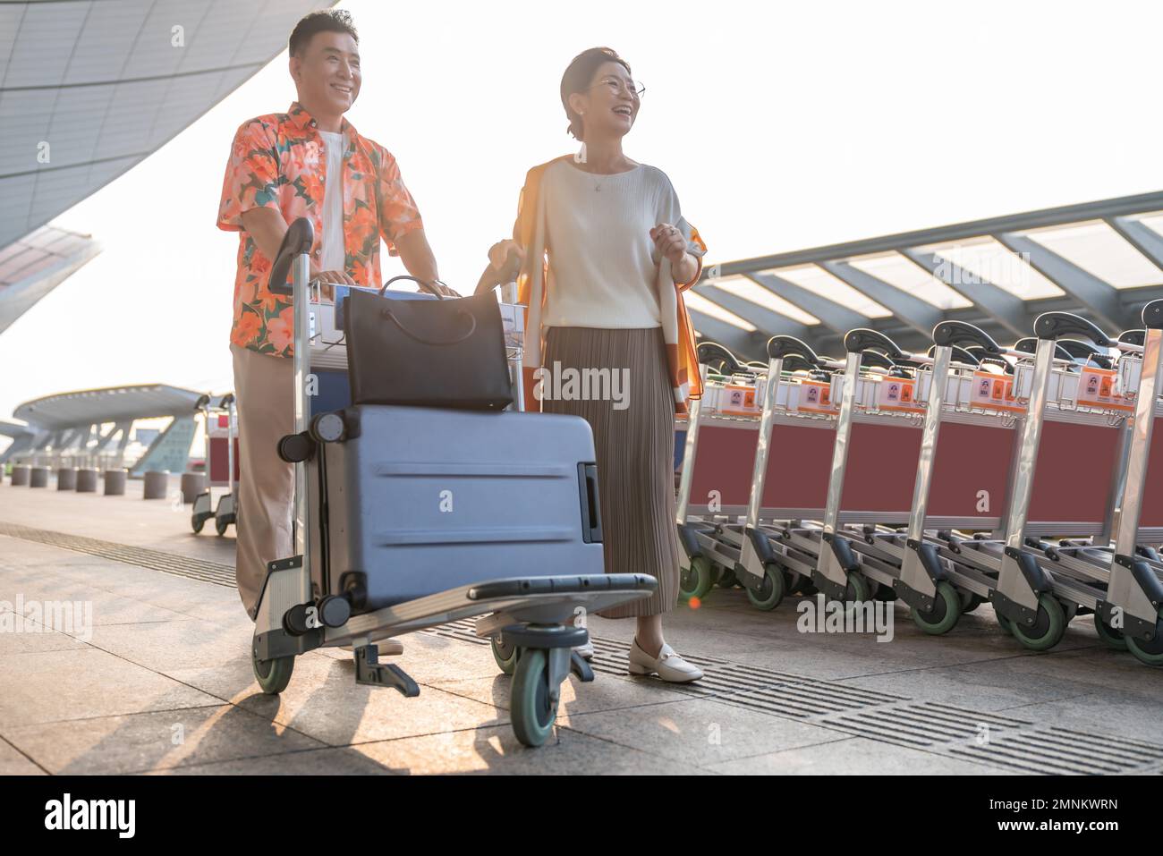 Happy older couples pushing a cart at the airport Stock Photo - Alamy