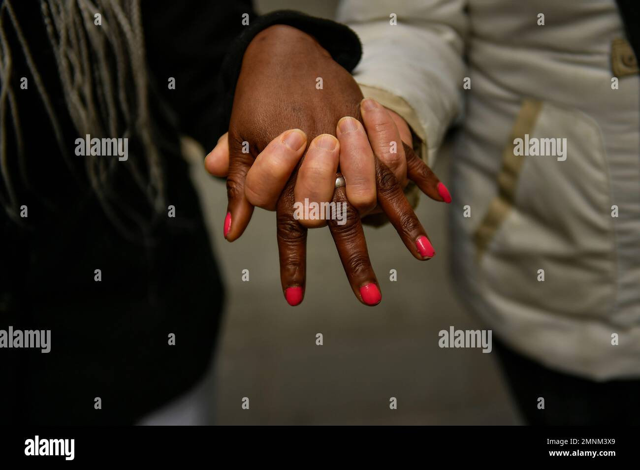 Black and white females hold hands in support of refugees and migrants ...