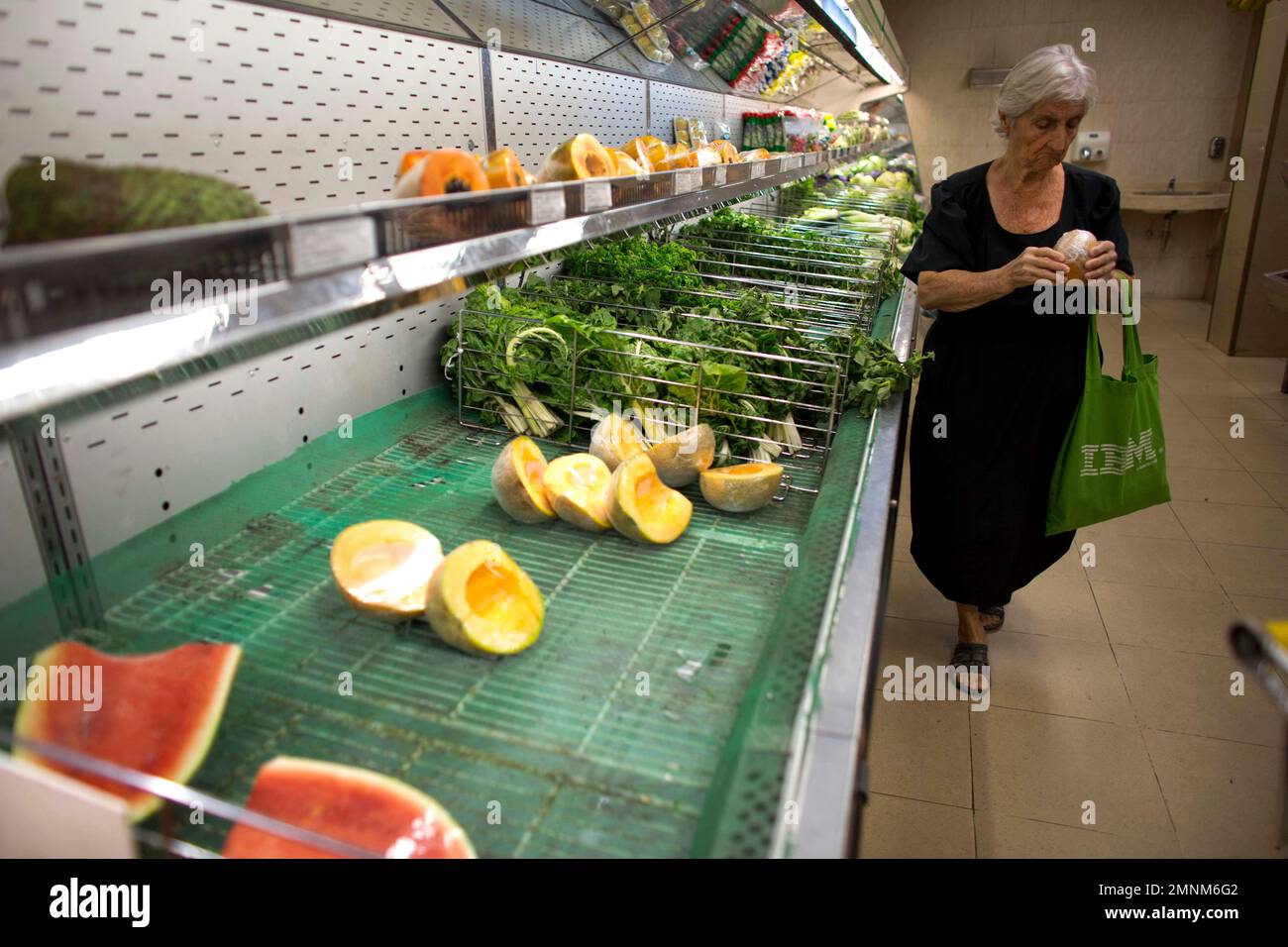 A woman looks at the price of a melon at a supermarket in Caracas ...