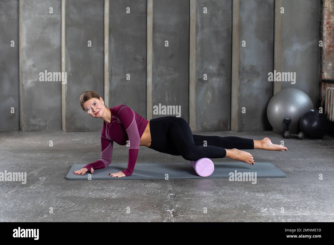 A young woman in sportswear performs a myofascial massage of the lower ...