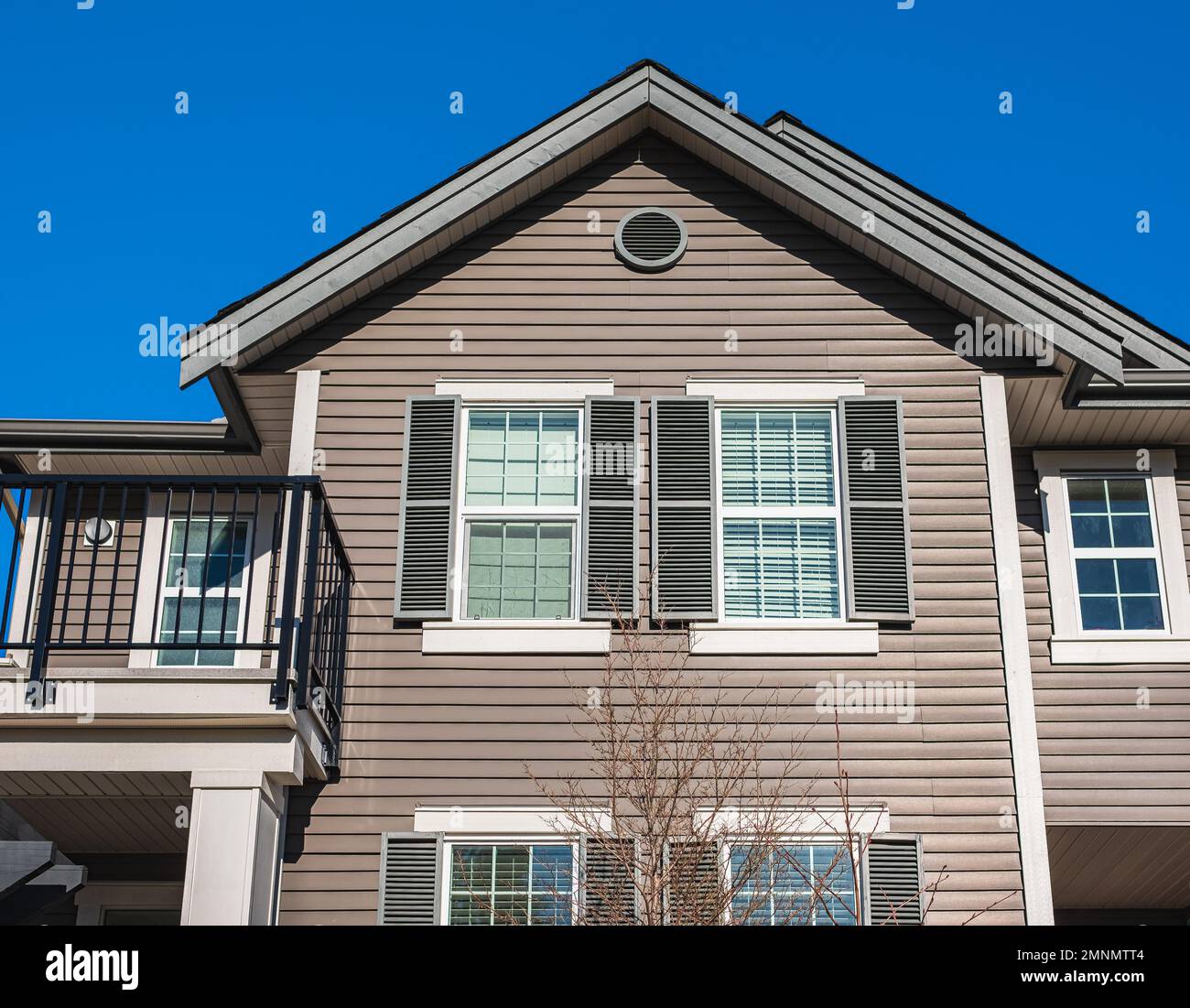 Top of a house with nice windows. Dormer in the blue sky background ...