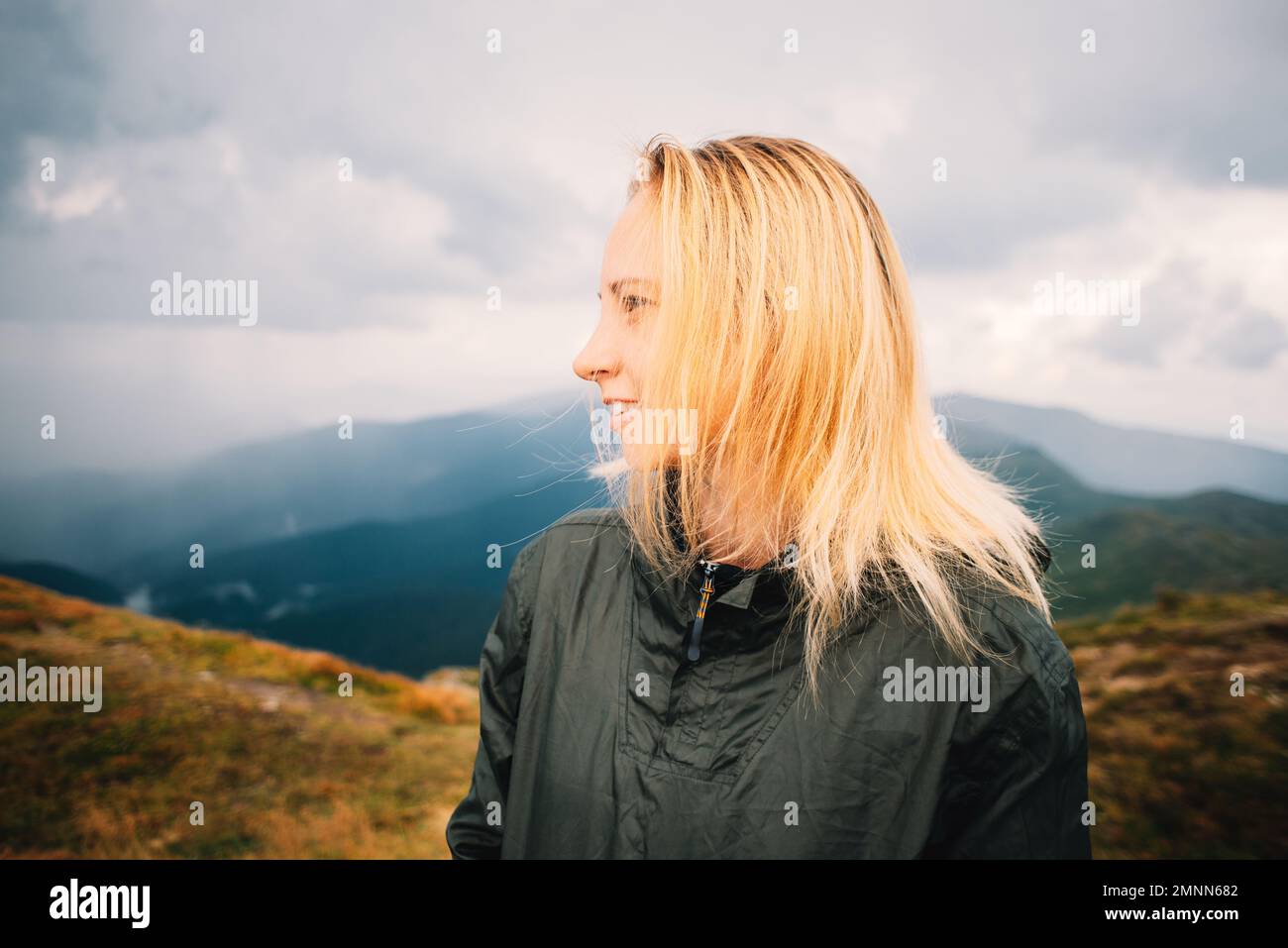 Cute a young blonde female hacker a rain jacket smiling against the ...
