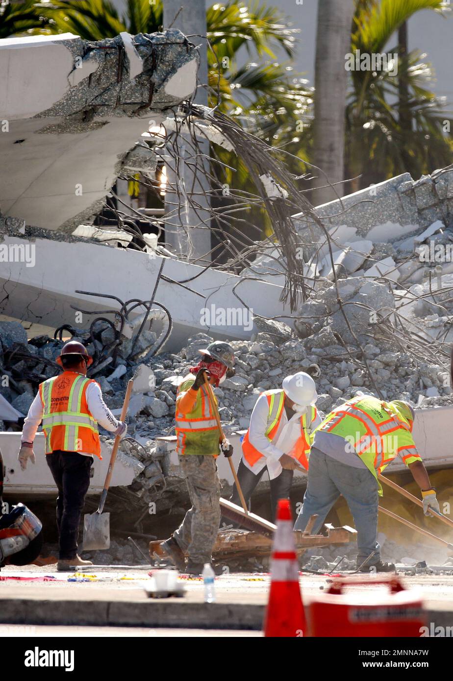 Workers remove debris from a new pedestrian bridge, Friday, March 16 ...
