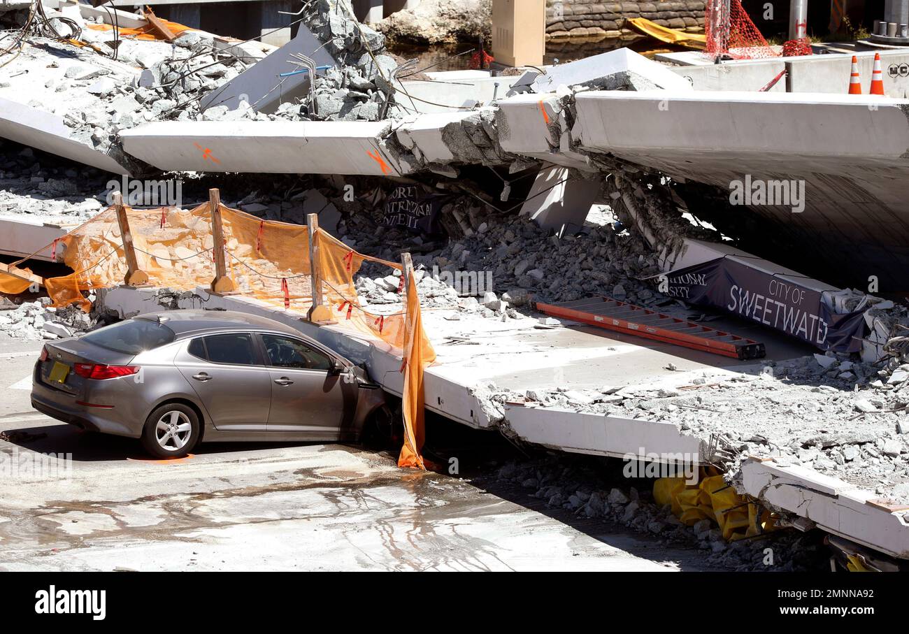 Crushed cars are shown under a section of a collapsed pedestrian bridge ...