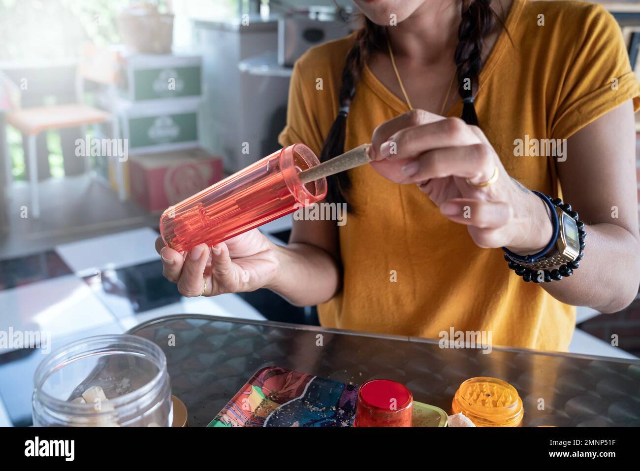 A Thai woman rolls a joint of a cigarette with marijuana using a ...