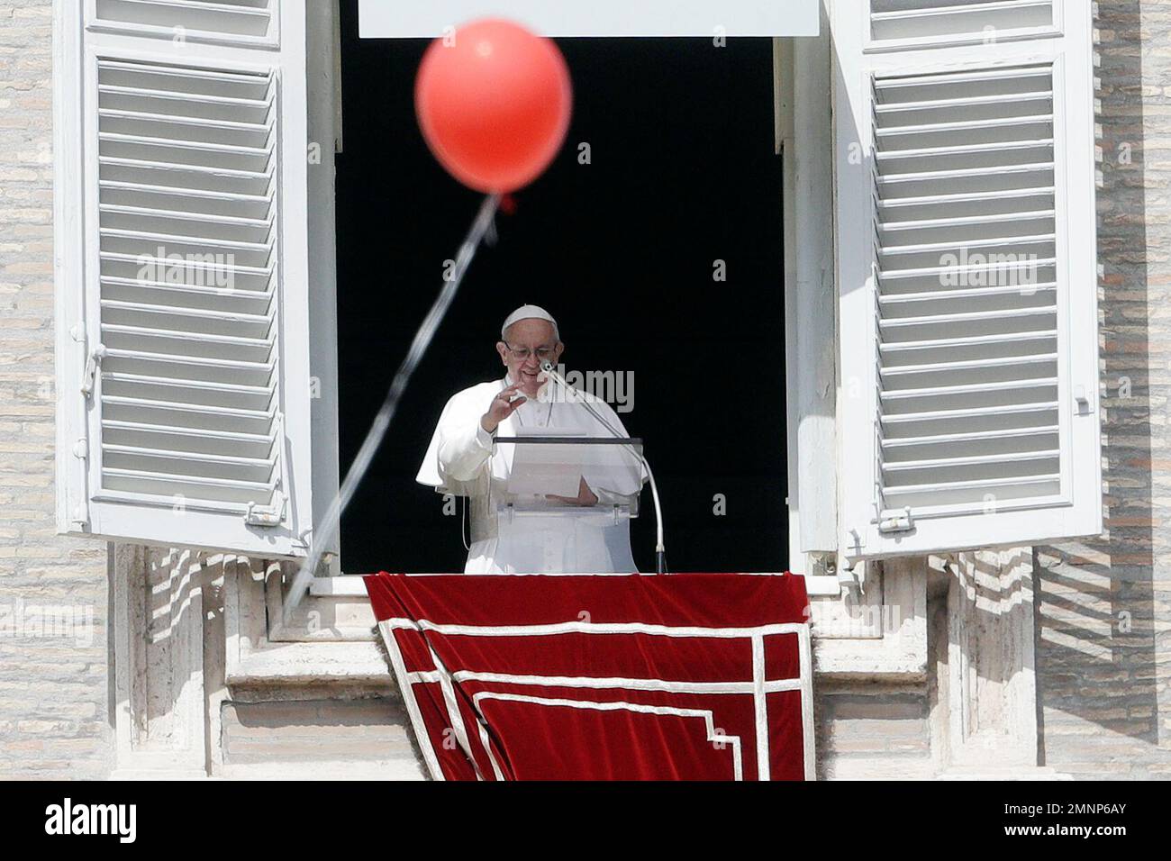 A red balloon flies in front of Pope Francis as he recites the Angelus ...