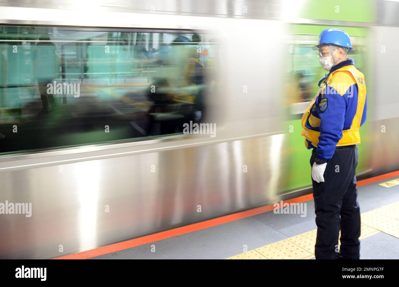 Railway safety worker standing on the platform of the JR Yamanote line ...