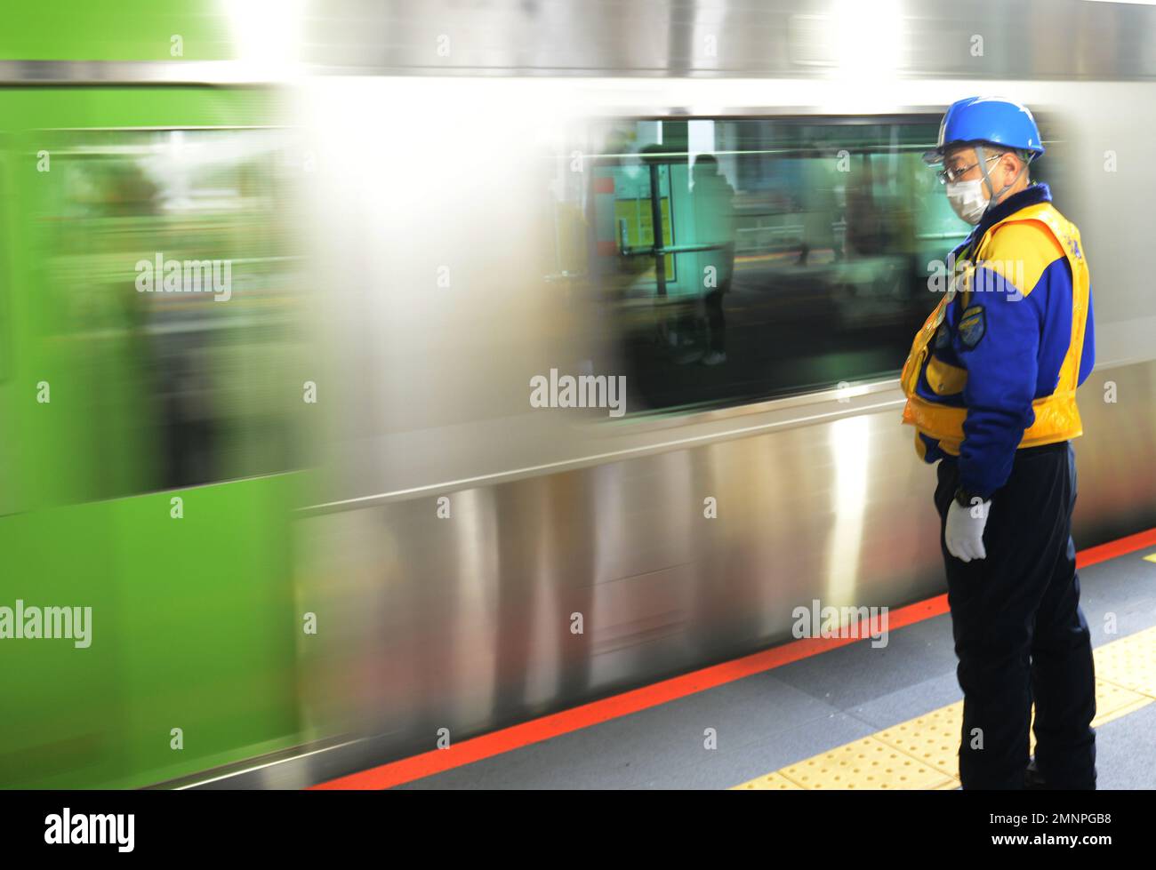 Railway safety worker standing on the platform of the JR Yamanote line ...