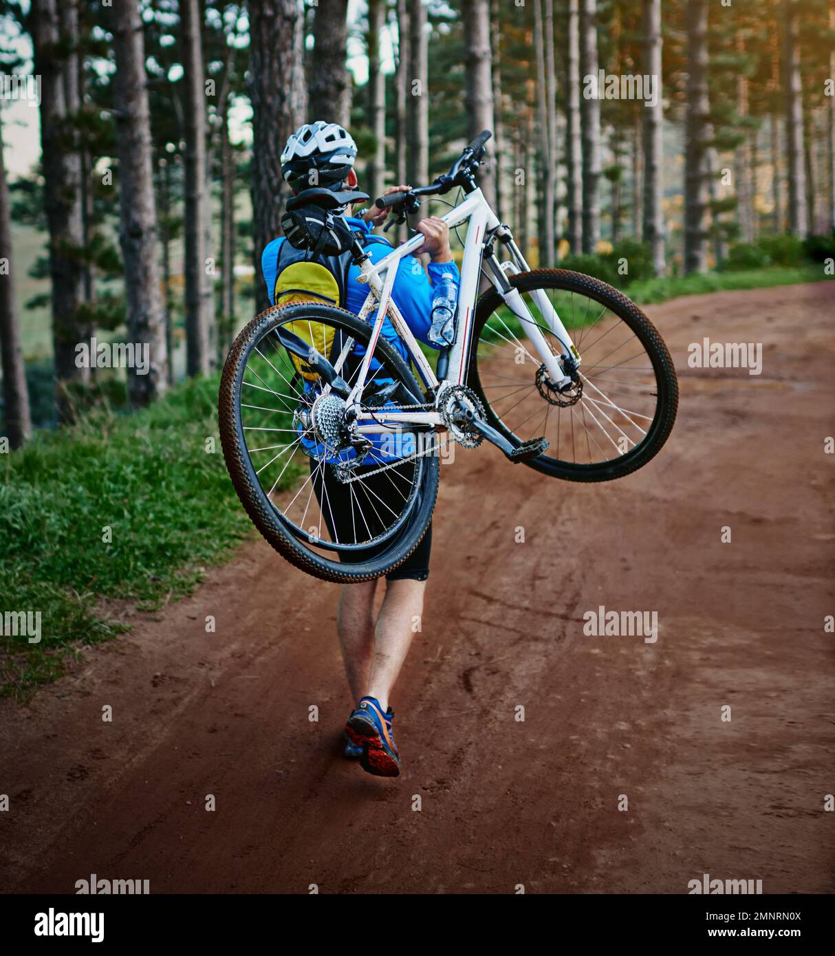 Mountain bikers are a tough lot. a male cyclist walking along a trail ...