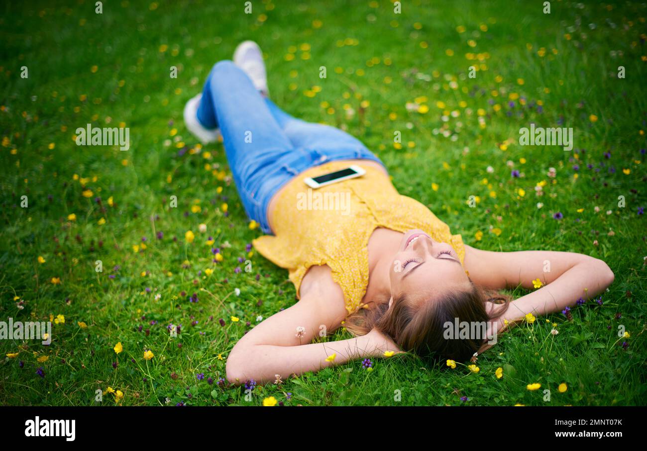 Living life wide open. a young woman lying down in a field of grass ...