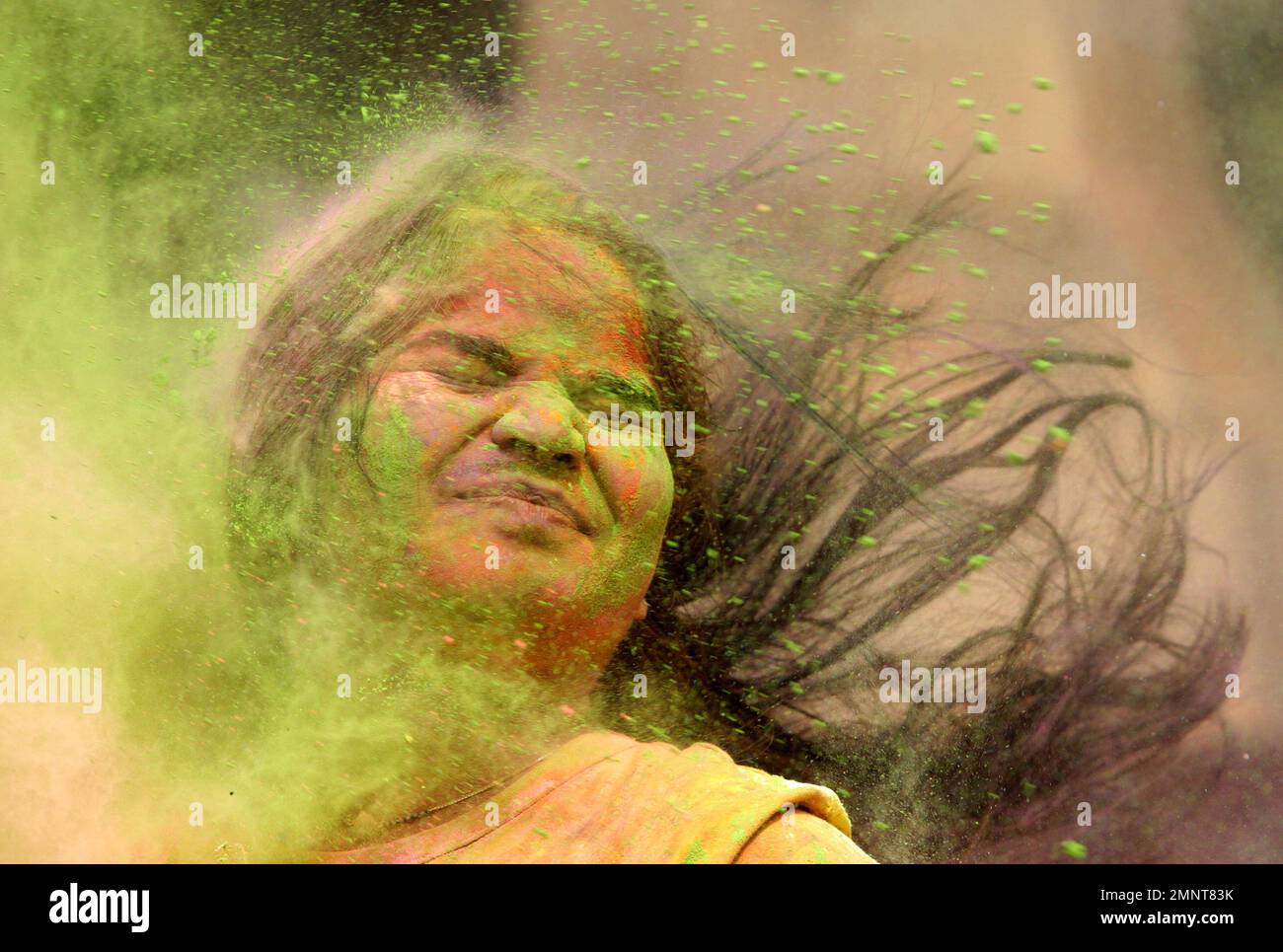 An Indian girl reacts as colored powder is thrown at her during ...