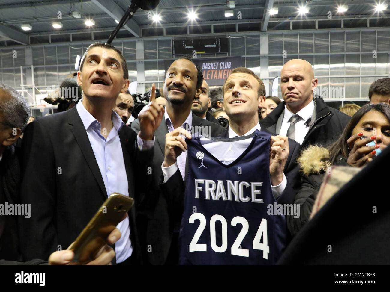 French President Emmanuel Macron, center, holding an Olympic 2024 ...