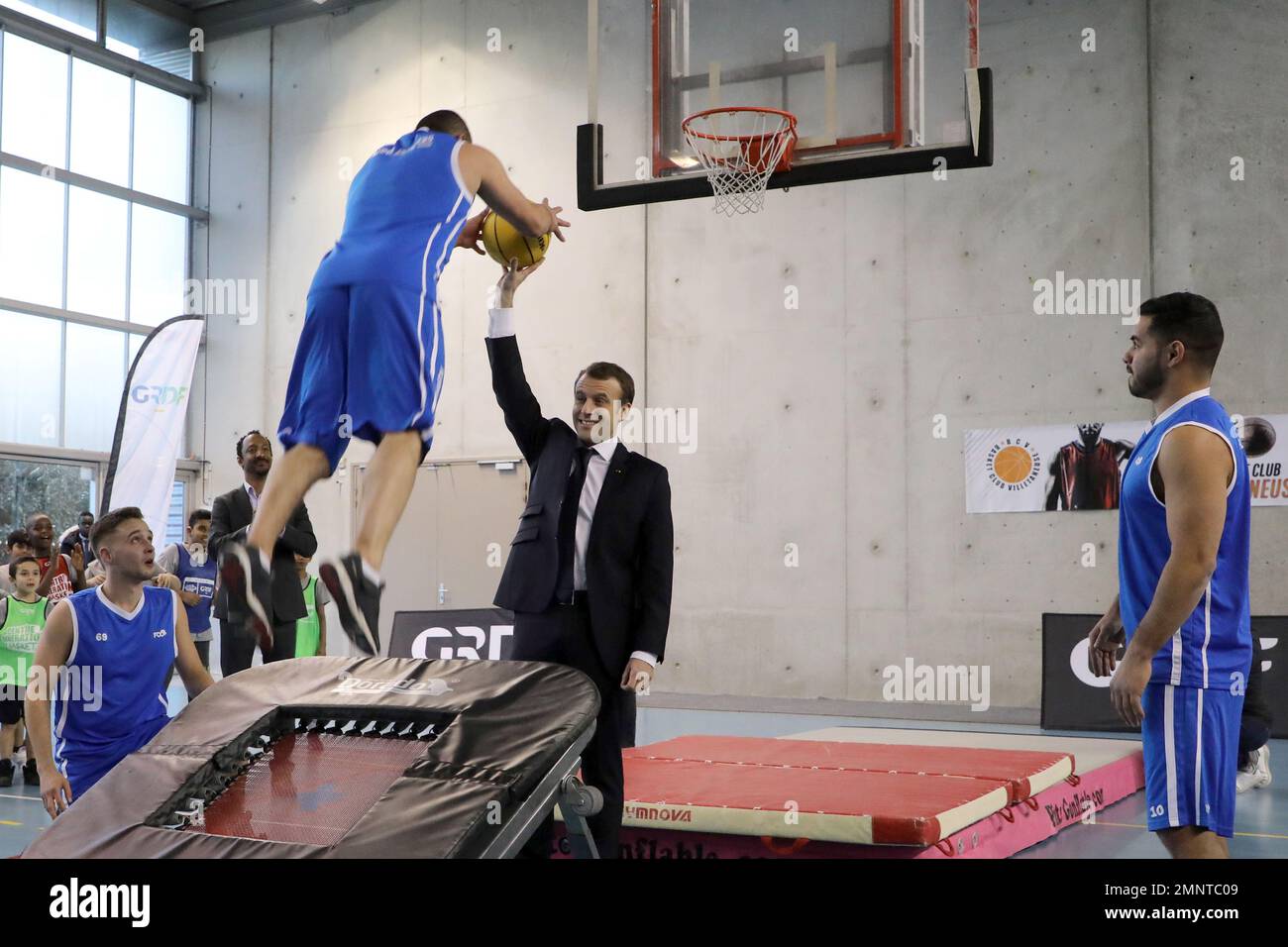 French President Emmanuel Macron holds up a ball as a player exhibits ...