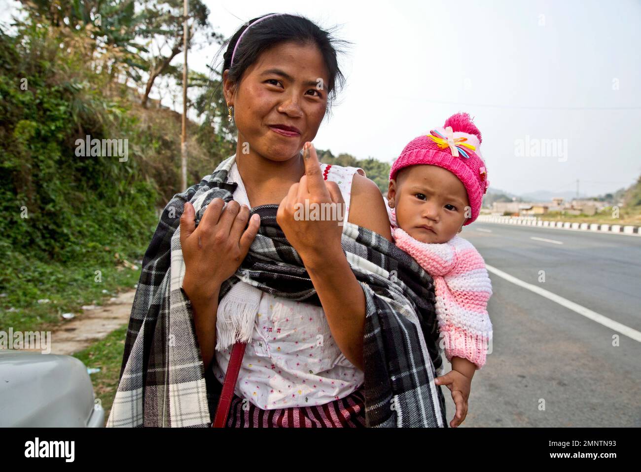 An Indian Khasi tribal woman carrying her child shows her ink mark ...