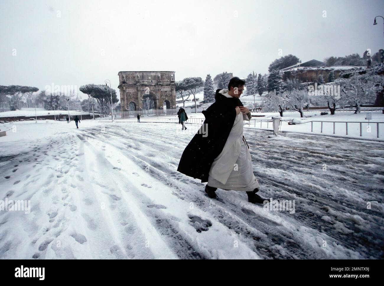 A priest walks past the The Arch of Constantine, between the Colosseum ...