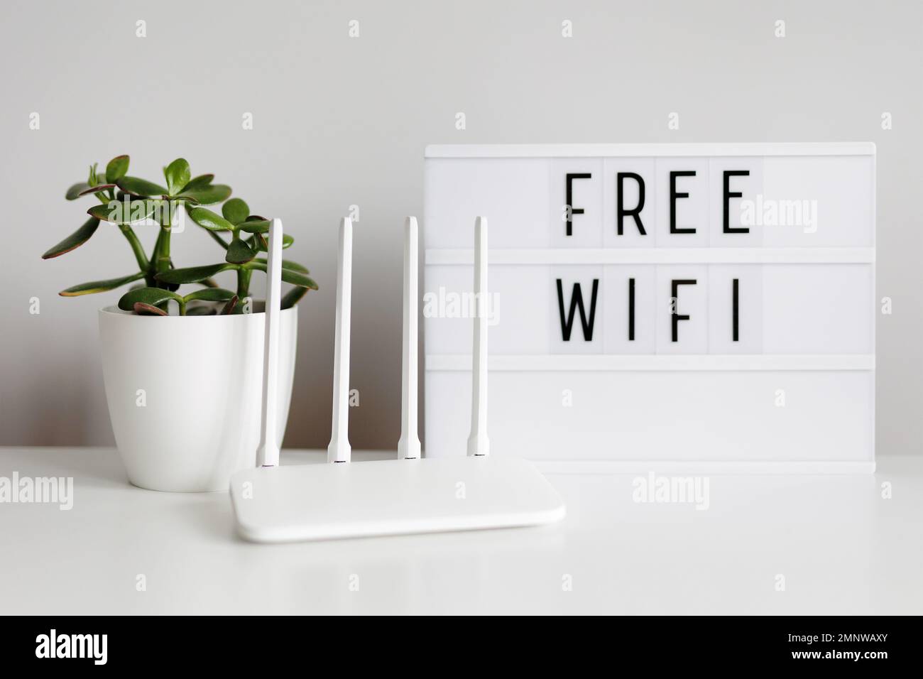 White router, plant and lightbox with free wifi text on table Stock ...