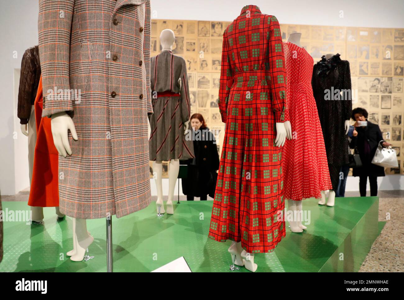 A woman takes pictures to designer clothes displayed at the exhibit ...