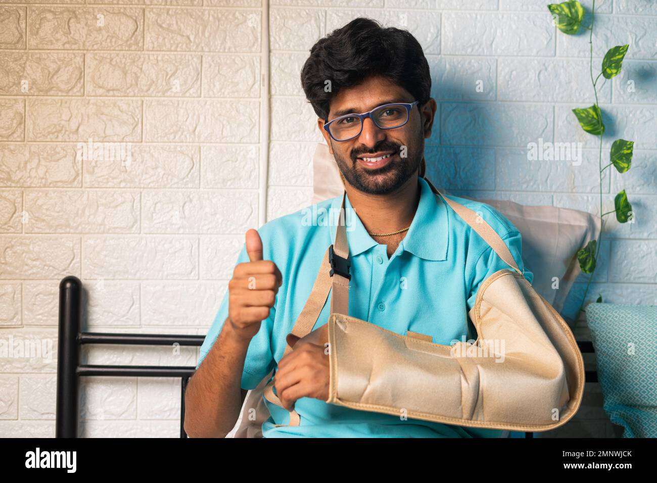 happy smiling young man with broken hand at bedroom showing thumbs up ...