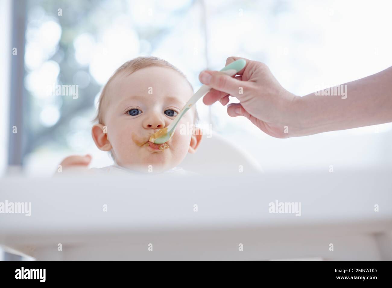 Enjoying every mouthful. Low angle view of a baby boy being fed by his ...