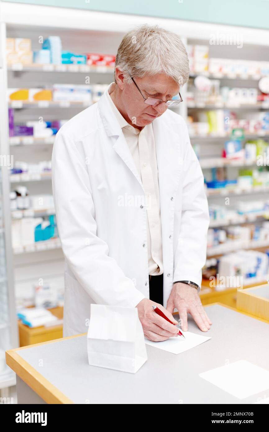 Portrait of a confident pharmacist writing prescription with medicines ...