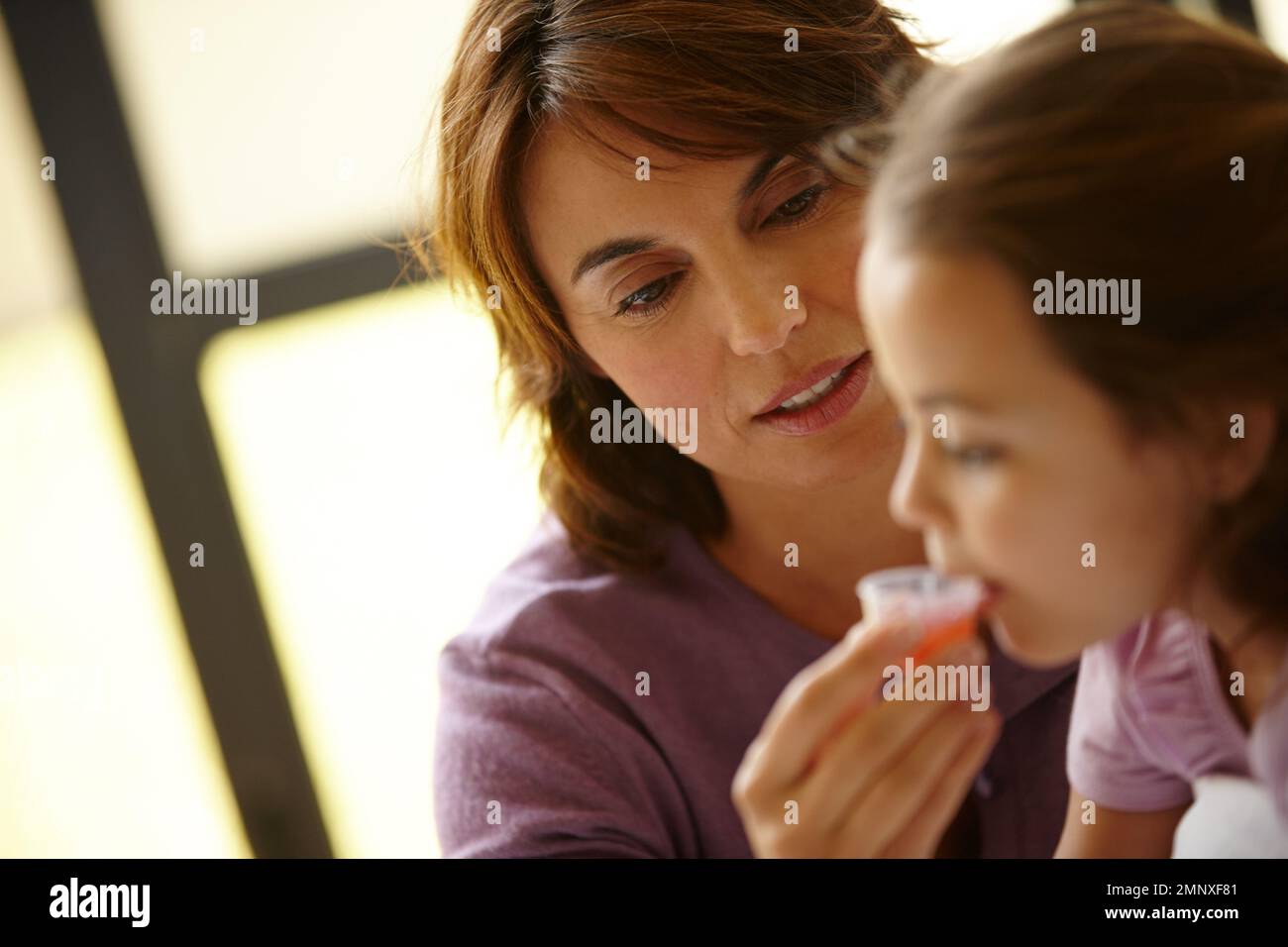 This will make it better. a mother giving her daughter medicine Stock ...