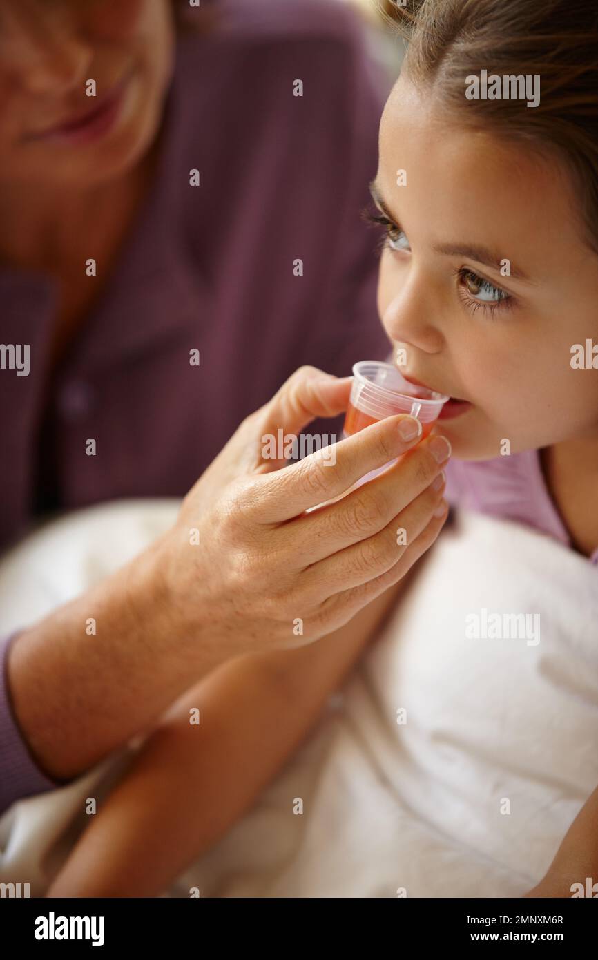 Mom makes everything better. a mother giving her daughter medicine ...